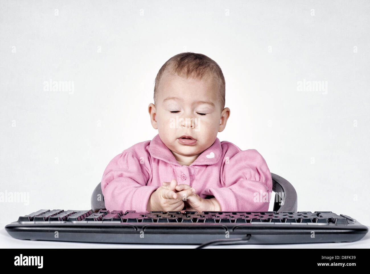 Tired baby sitting at the keyboard Stock Photo - Alamy