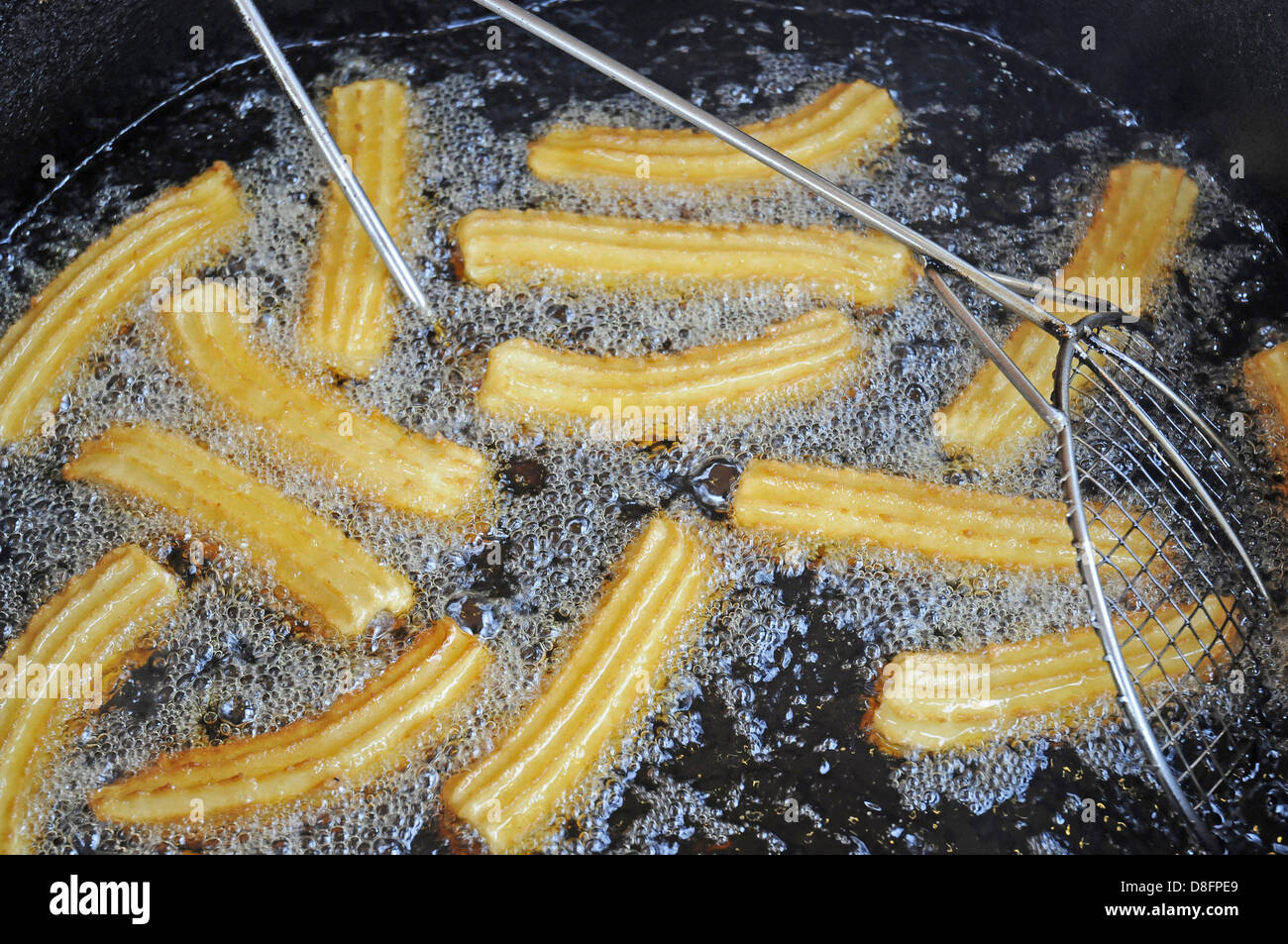 Churros in hot fat Stock Photo - Alamy