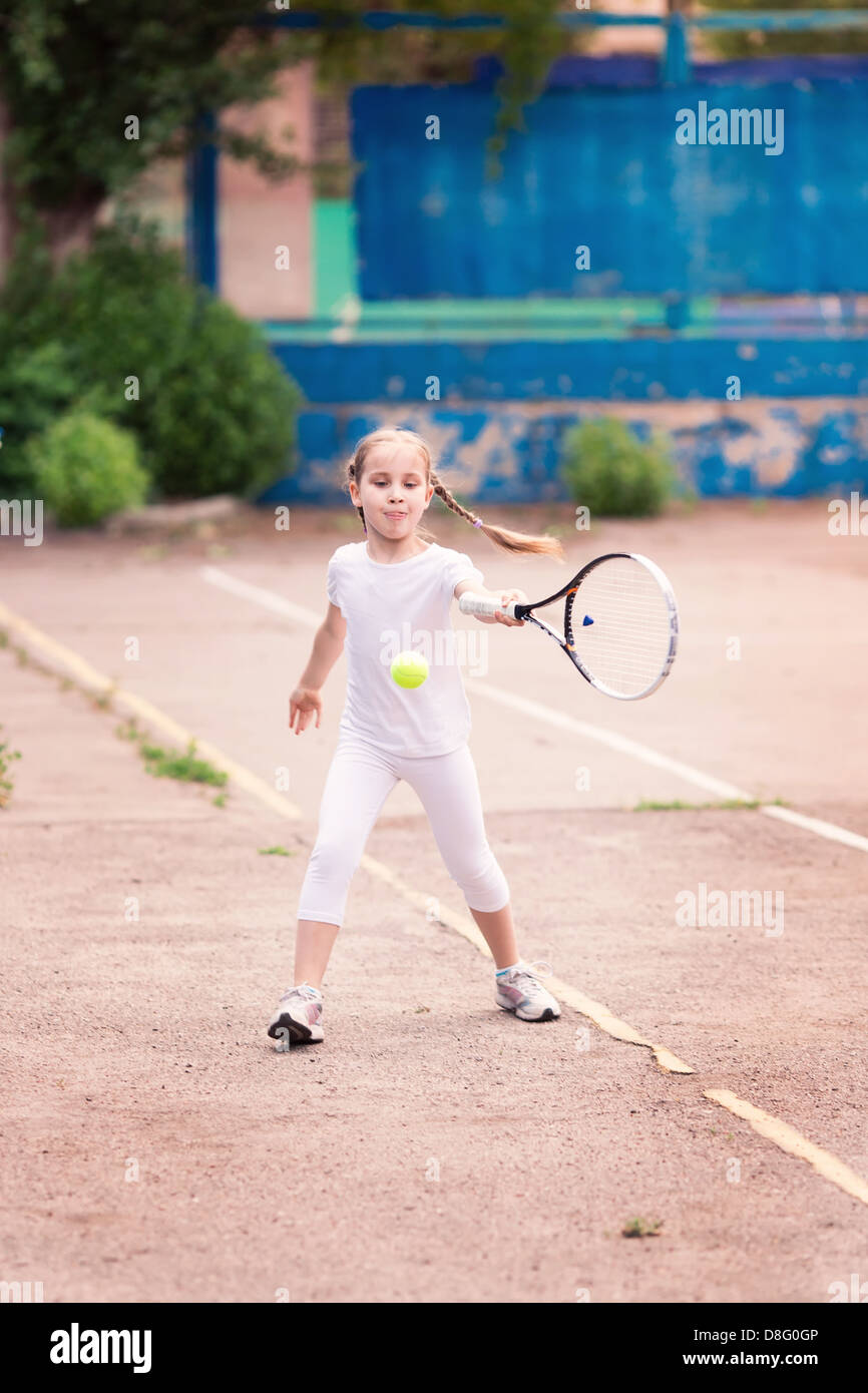 Adorable little child playing tennis with racket and a ball on tennis ...