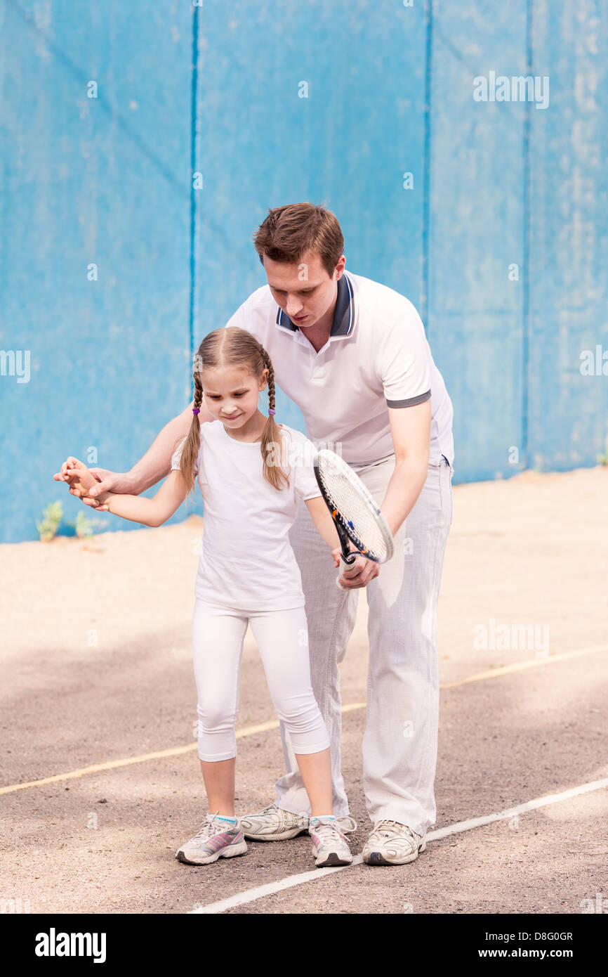 Instructor teaching a child how to play tennis on a court outdoor Stock ...