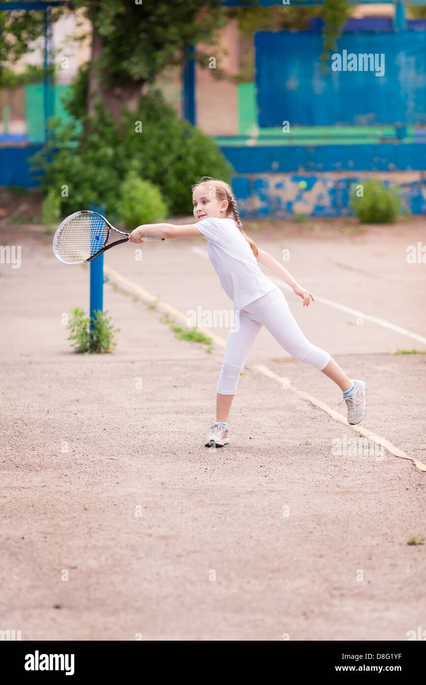 Adorable little child playing tennis with racket and a ball on tennis ...