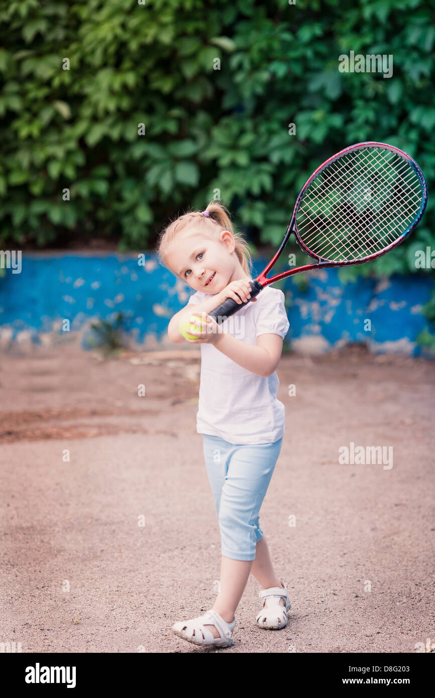 Adorable little child playing tennis with racket and a ball on tennis ...