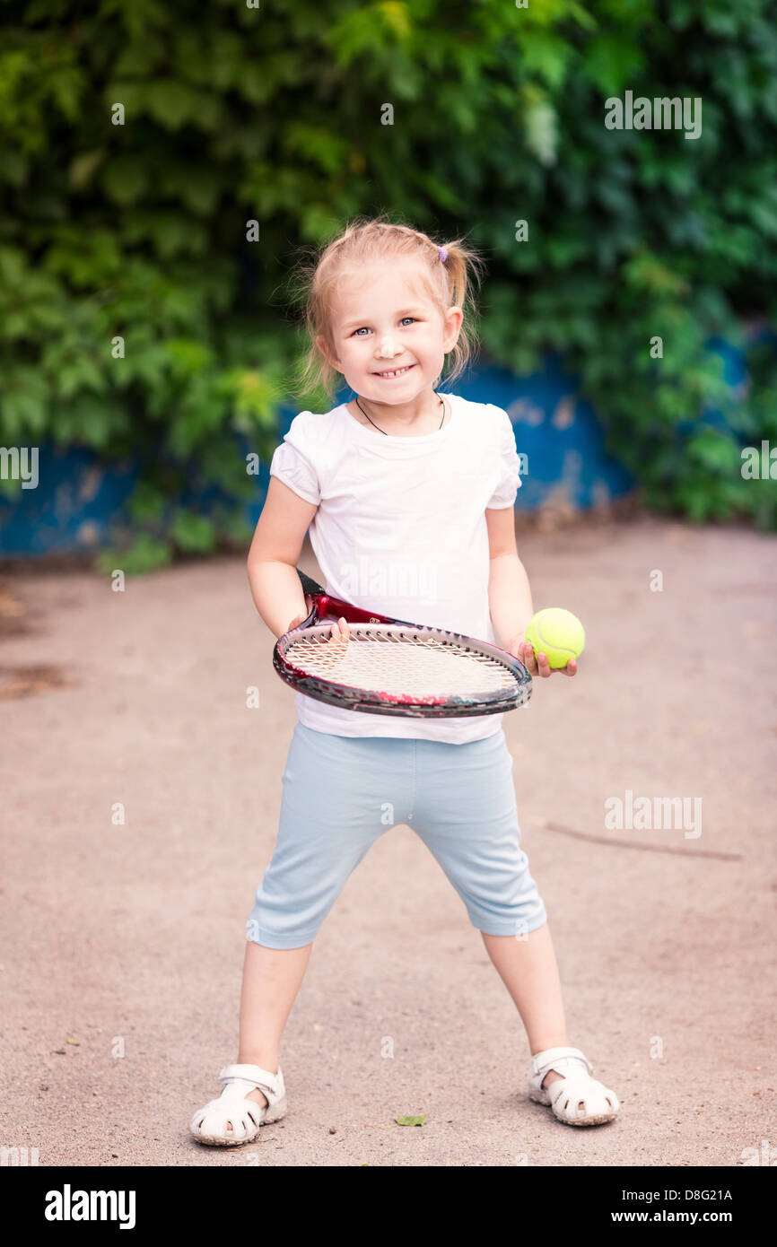 Adorable little child playing tennis with racket and a ball on tennis ...
