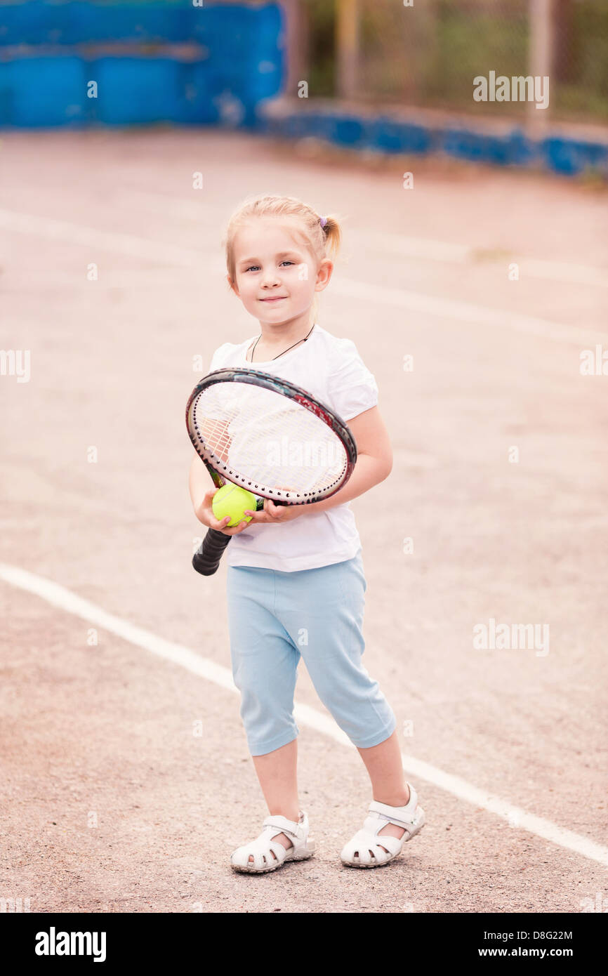 Adorable little child playing tennis with racket and a ball on tennis ...