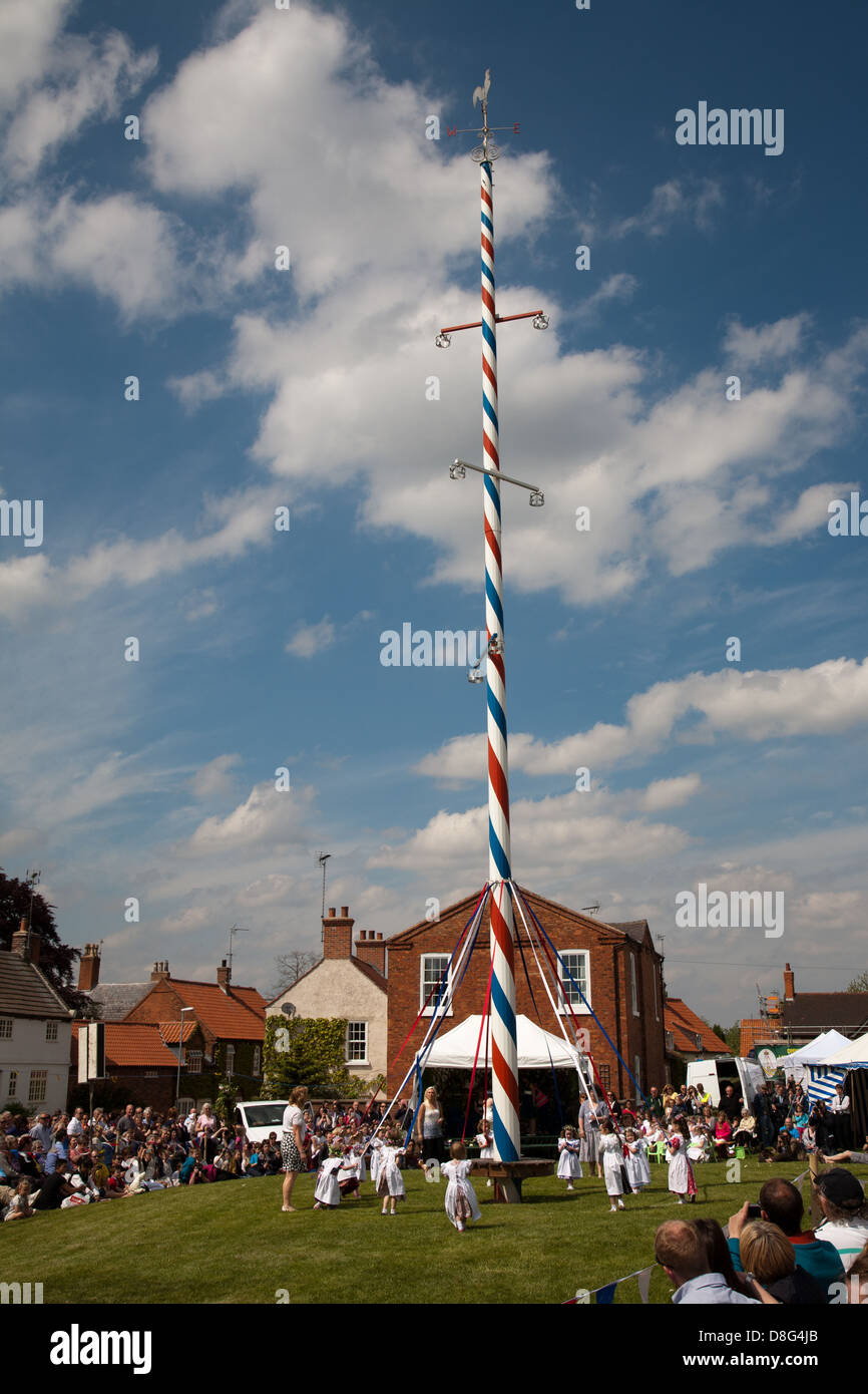 Children dance round the ancient maypole on the village green of Wellow ...