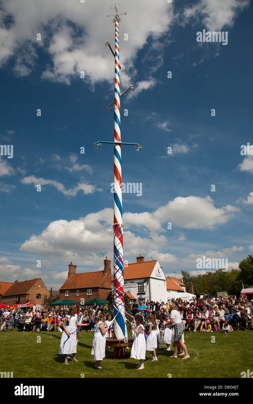 Children dance round the ancient maypole on the village green of Wellow ...