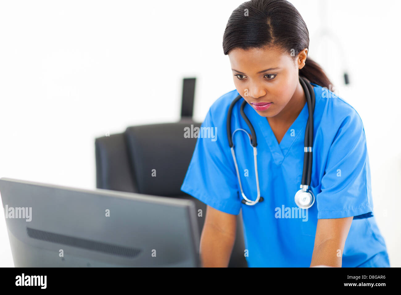 beautiful African nurse looking at computer screen in office Stock ...