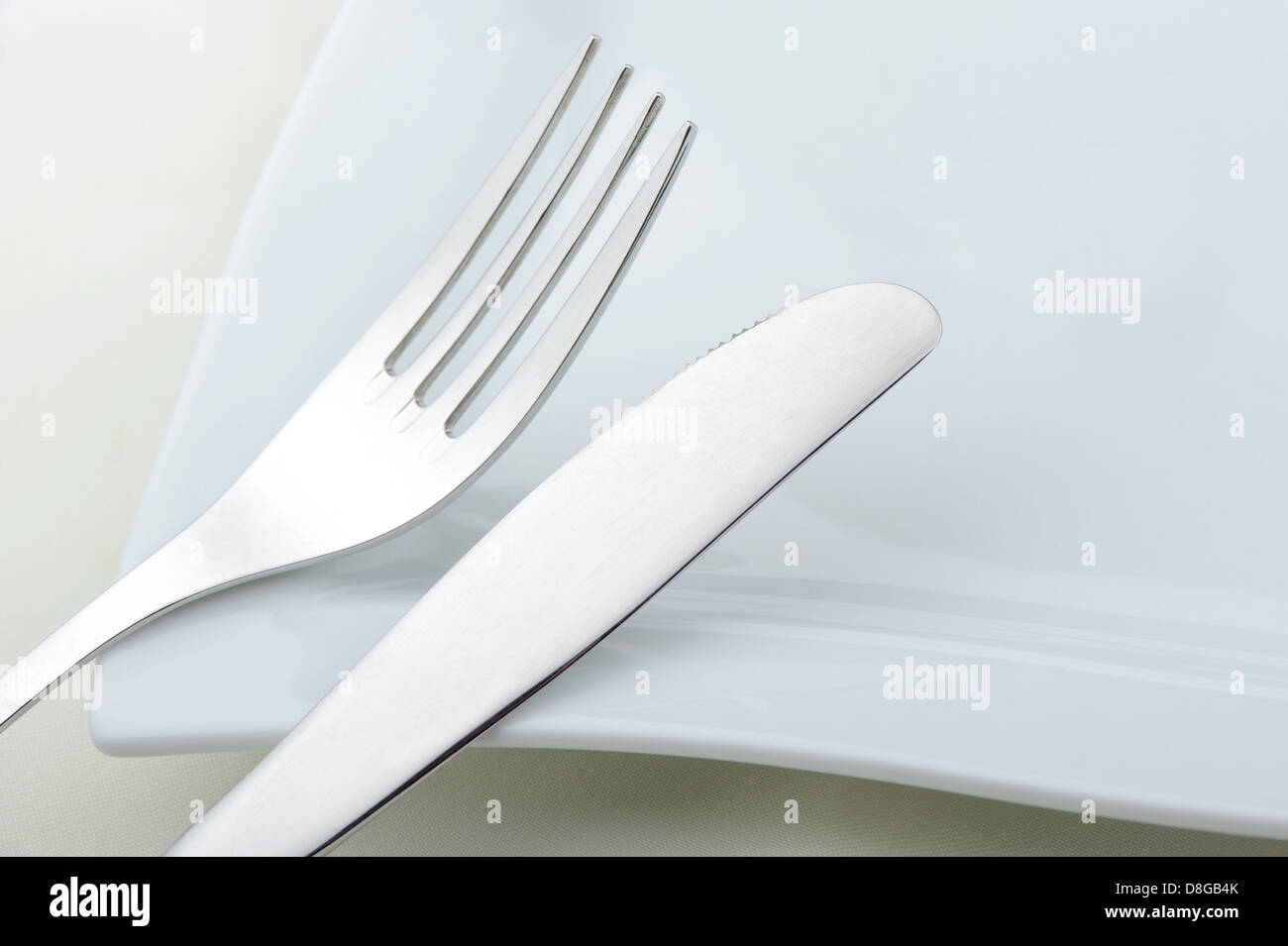 Fork and a knife laying on a plate Stock Photo - Alamy