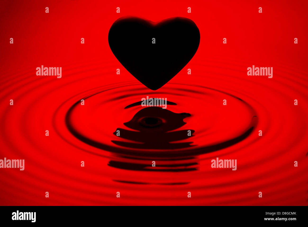 Black heart siluett over red water ripples Stock Photo - Alamy