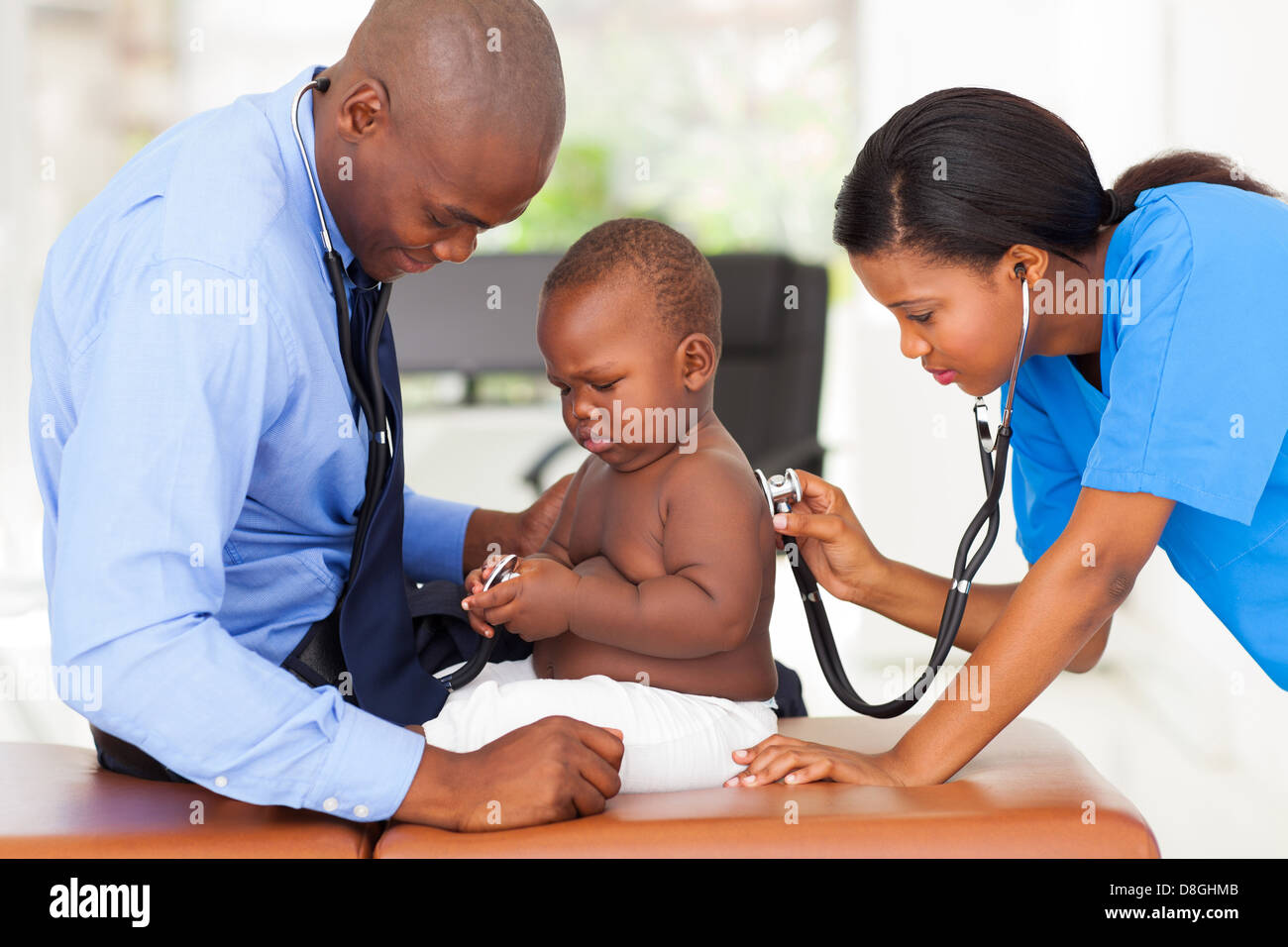 female African medical assistant examining a baby together with doctor ...