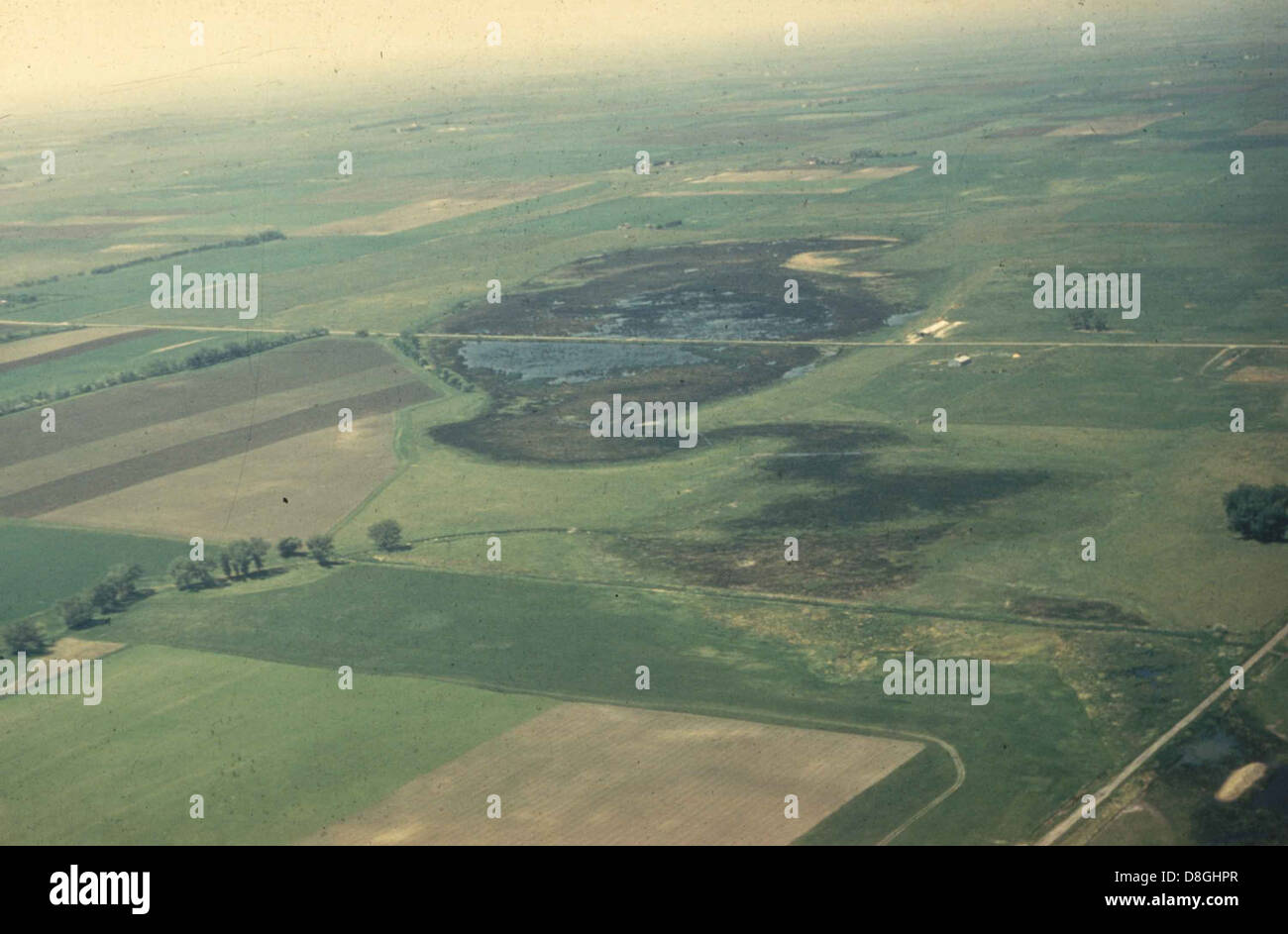 An aerial shot of a prairie pothole, a wetland feature, with a road ...