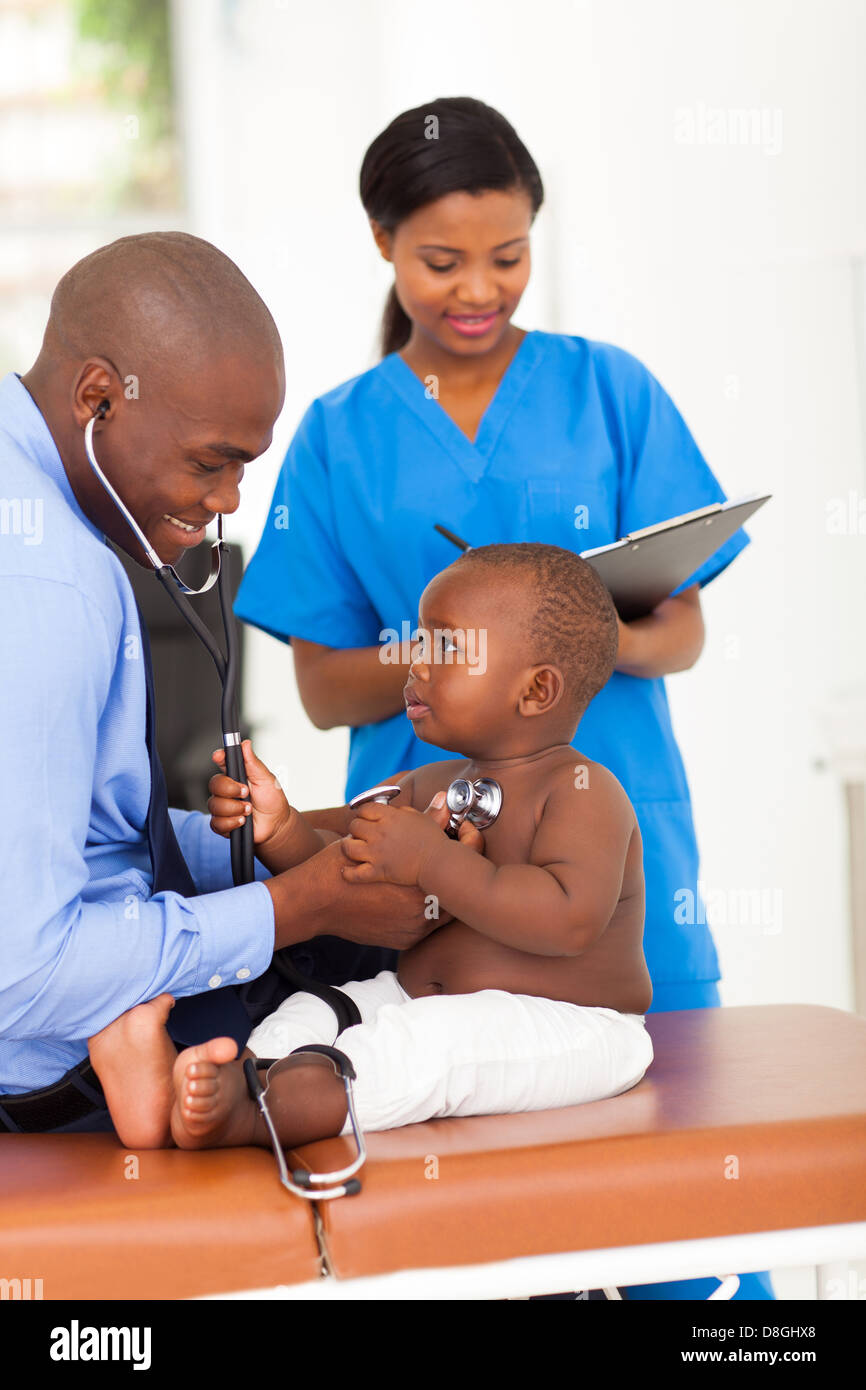 cute african little patient pulling doctor stethoscope during ...