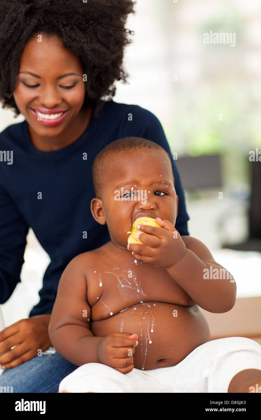 funny African baby boy eating an apple with milk spilt all over his ...