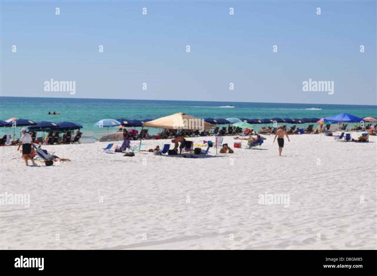 A group of people enjoying the beach, walking along the coastline. The ...
