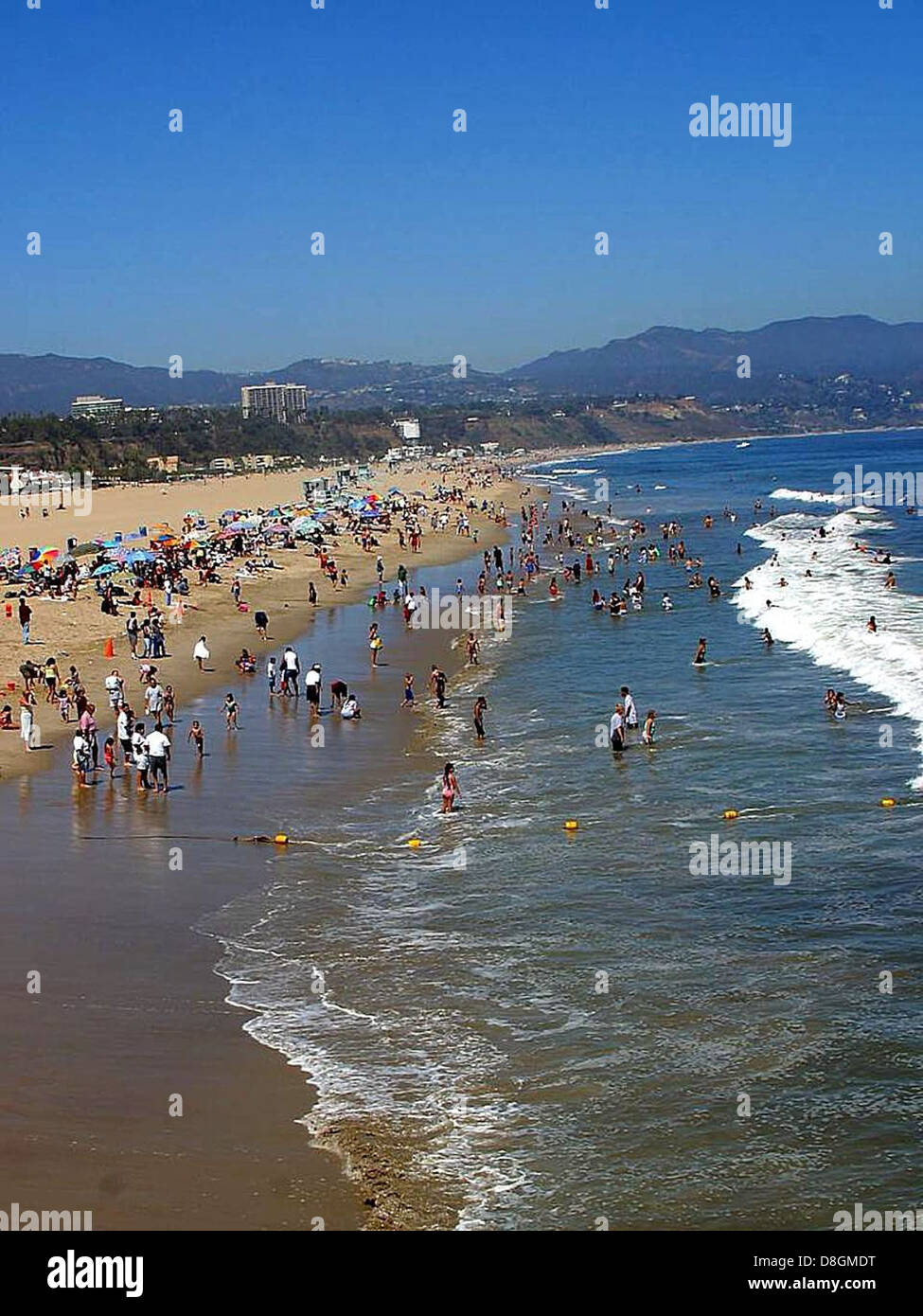 A beach scene with surfers riding waves in the ocean. The image ...