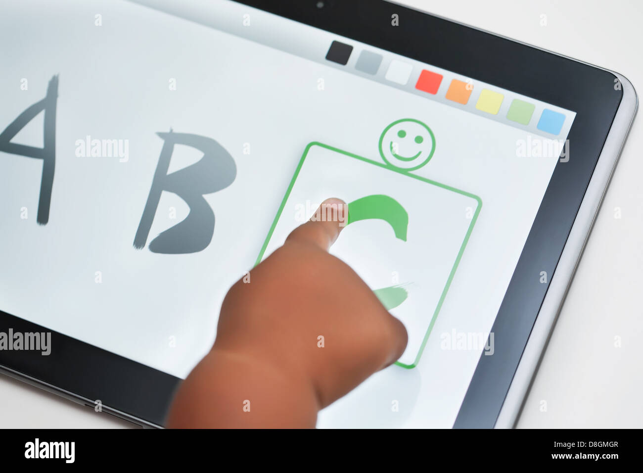 The finger of a toddler selecting the correct letter on a touchscreen ...