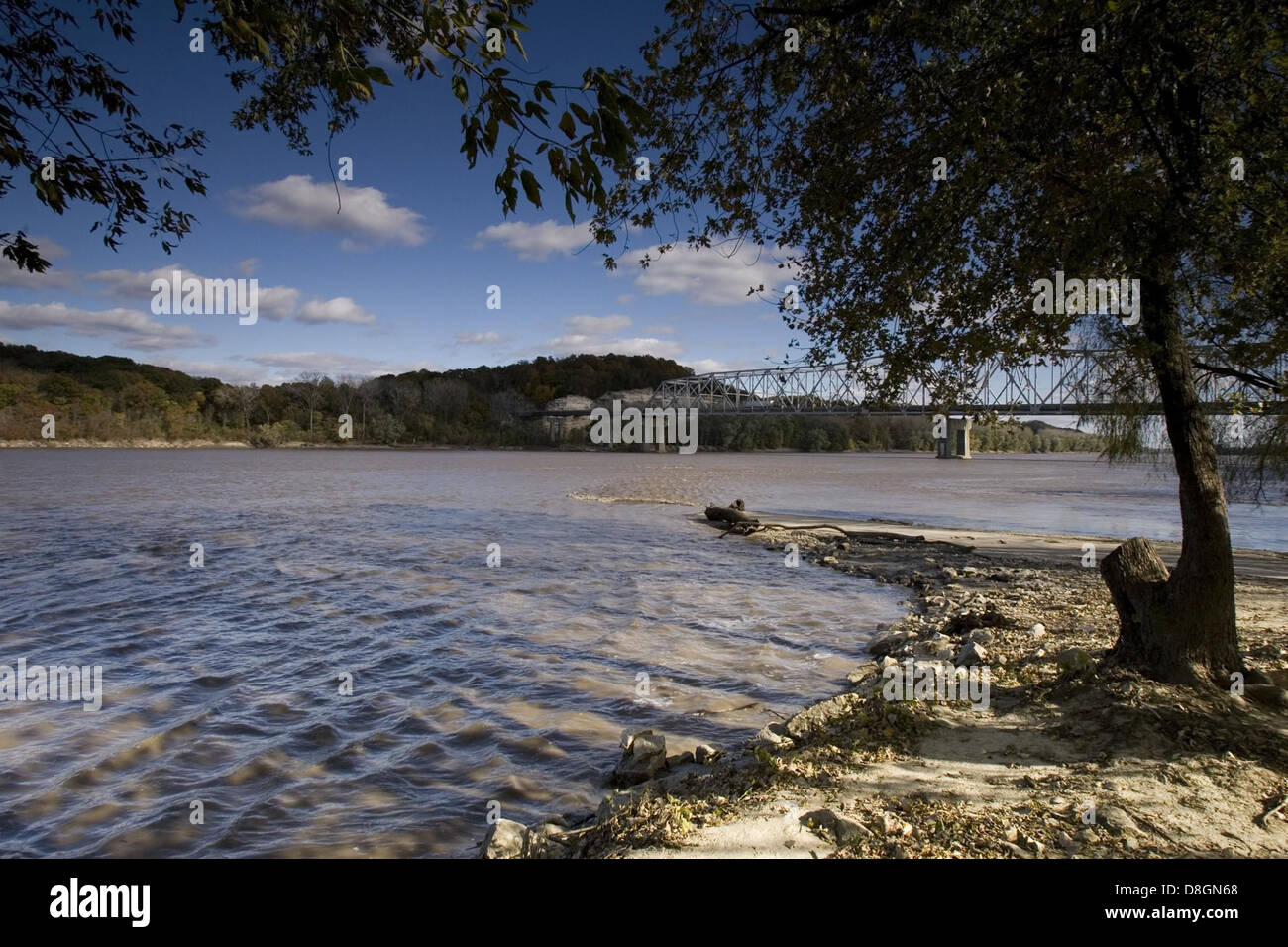 A view of a large, muddy shoreline with a highway bridge crossing over ...