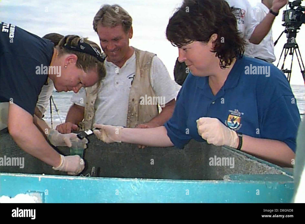 This image shows a biologist conducting fieldwork outdoors, surrounded ...