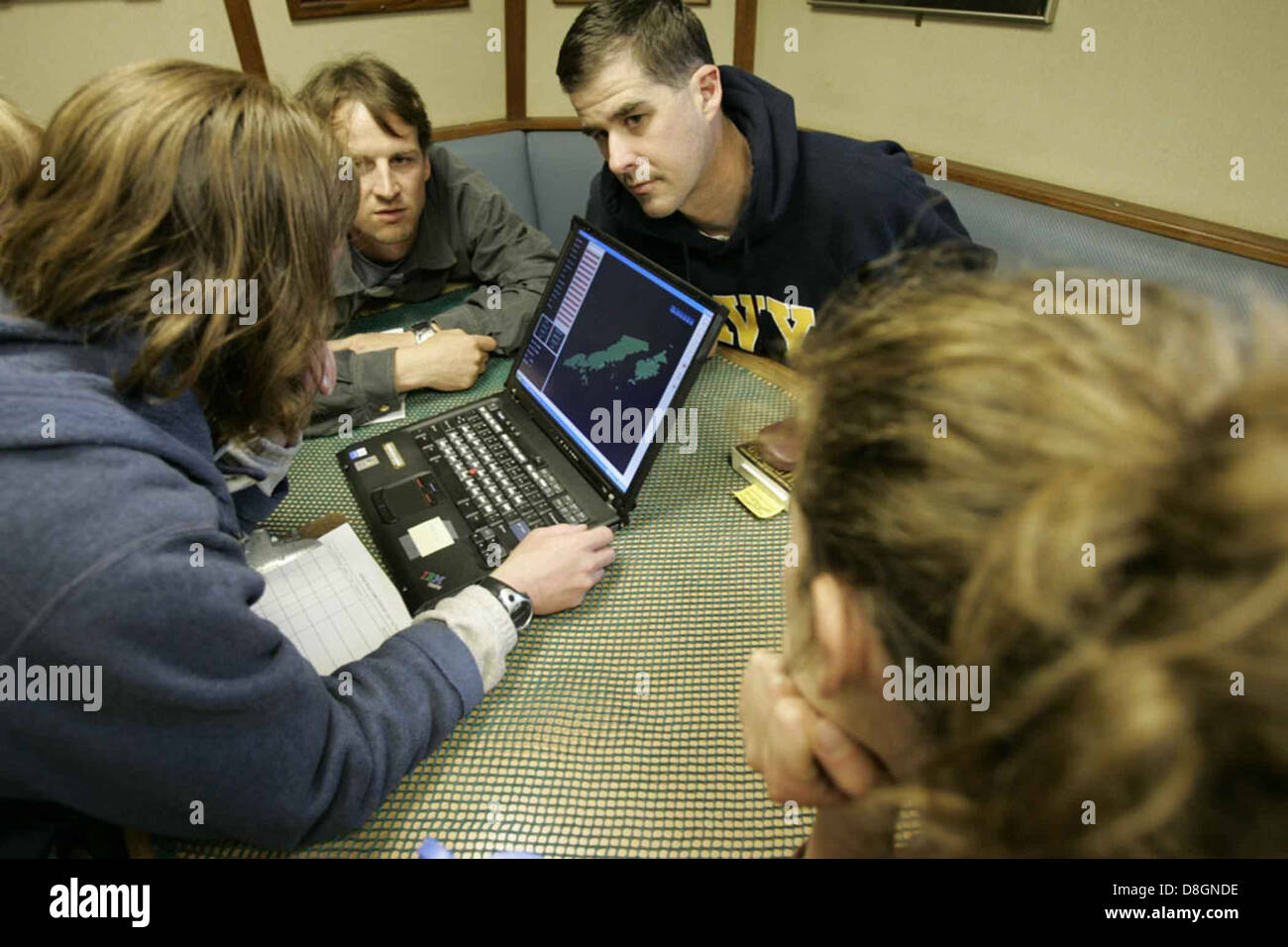 A biologist is seen working on board a research vessel, using a laptop ...