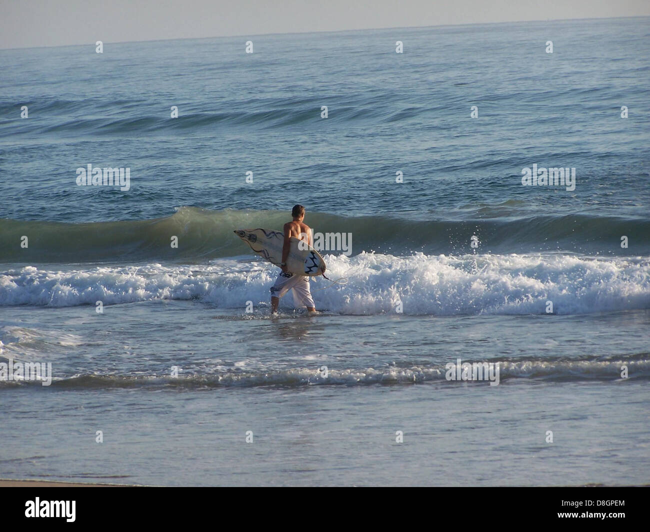 A person is seen wading into the water, perhaps preparing to swim or ...