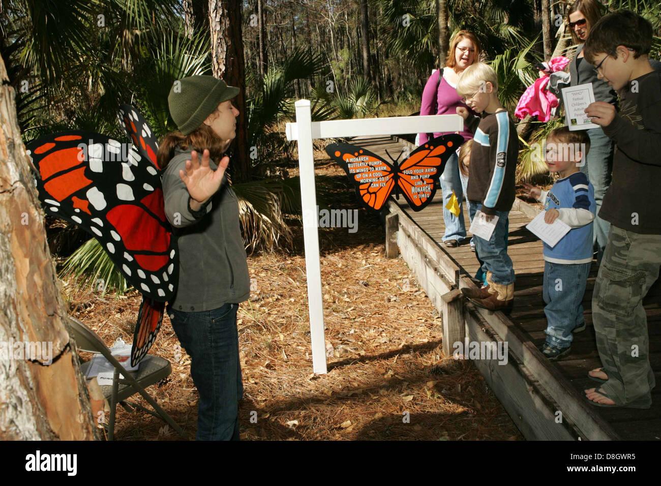 Children watching and enjoying a monarch butterfly at rest, observing ...