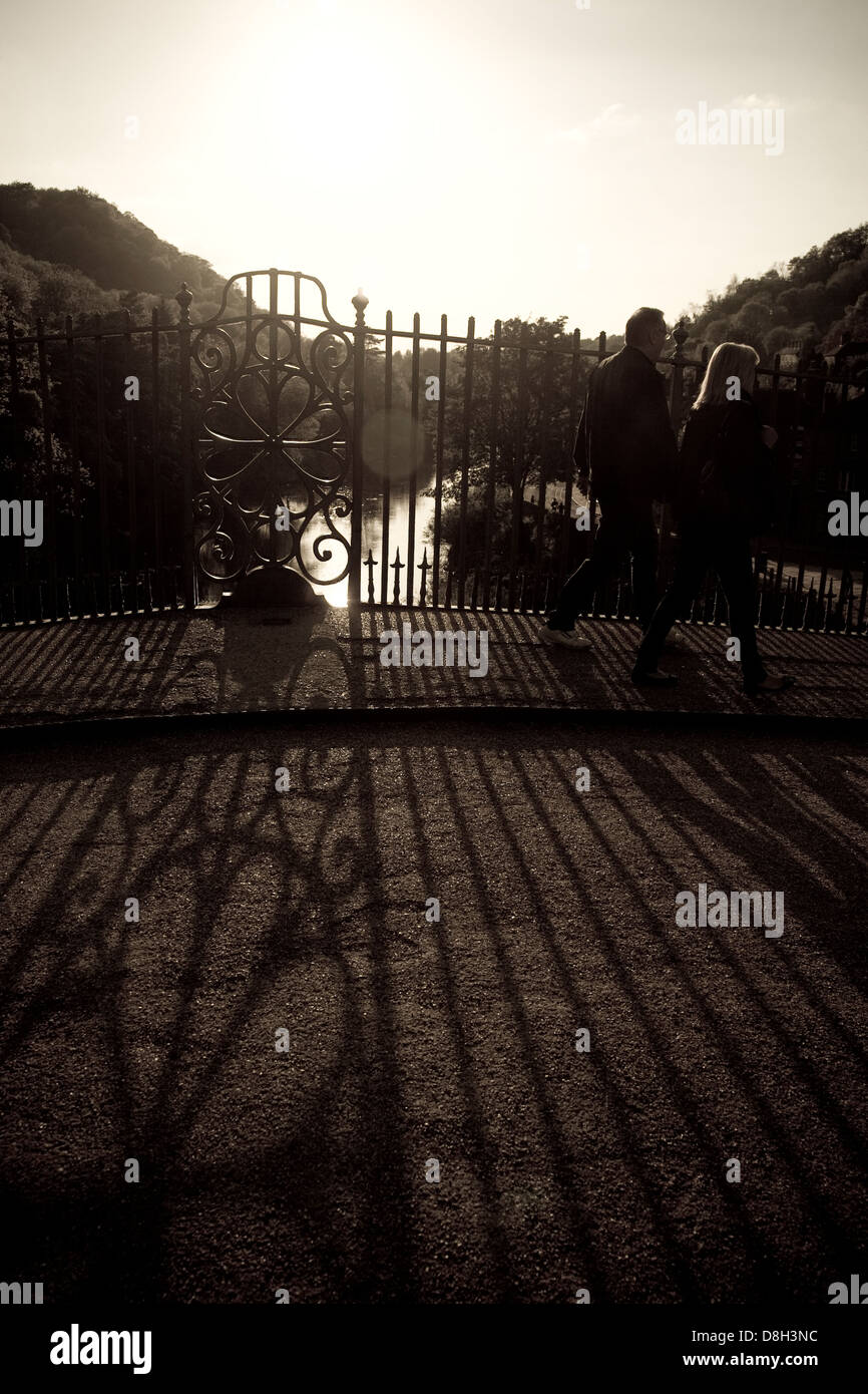 As the sun sets, a couple walk over the iron bridge at Ironbridge Gorge ...