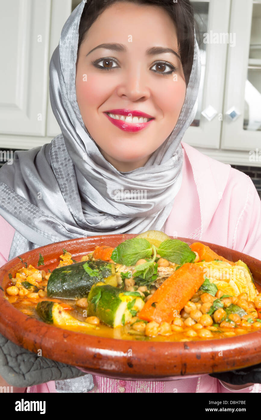 Smiling Moroccan immigrant woman in Europe presenting her tajine dish ...