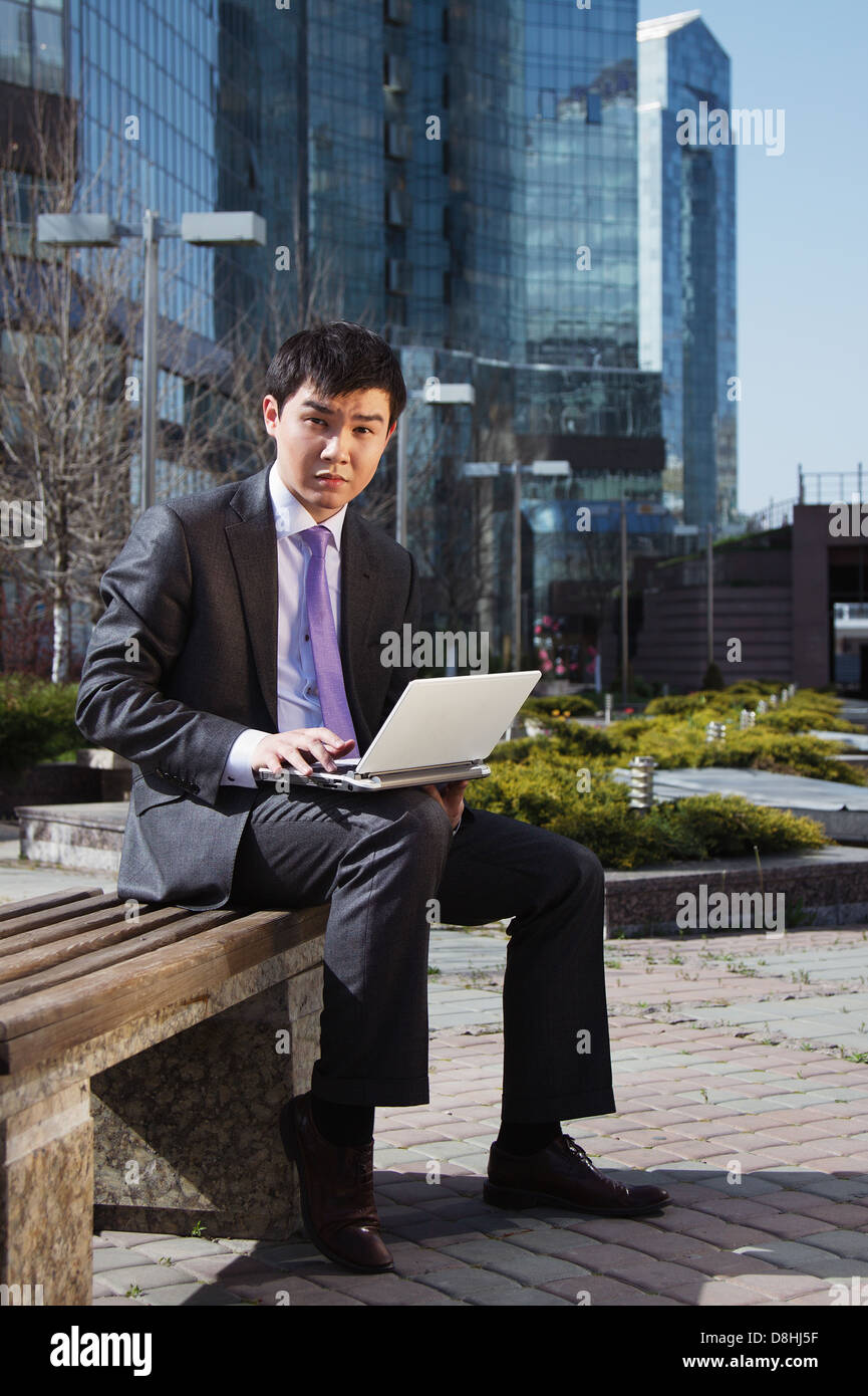 Young businessman sitting with laptop. Outdoor Stock Photo - Alamy