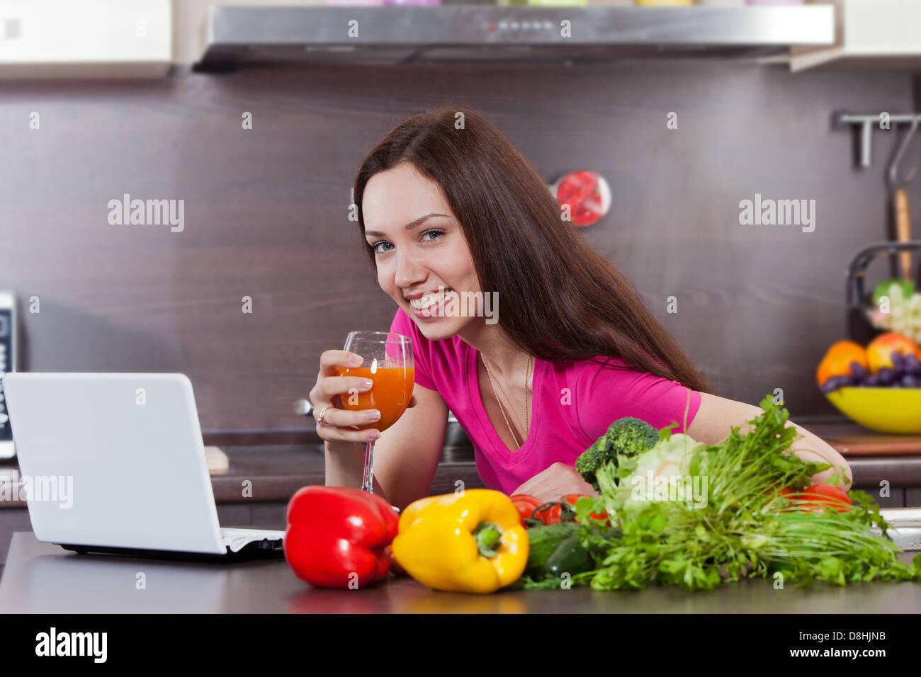 Woman drink the juice in the kitchen and looking at the computer Stock ...