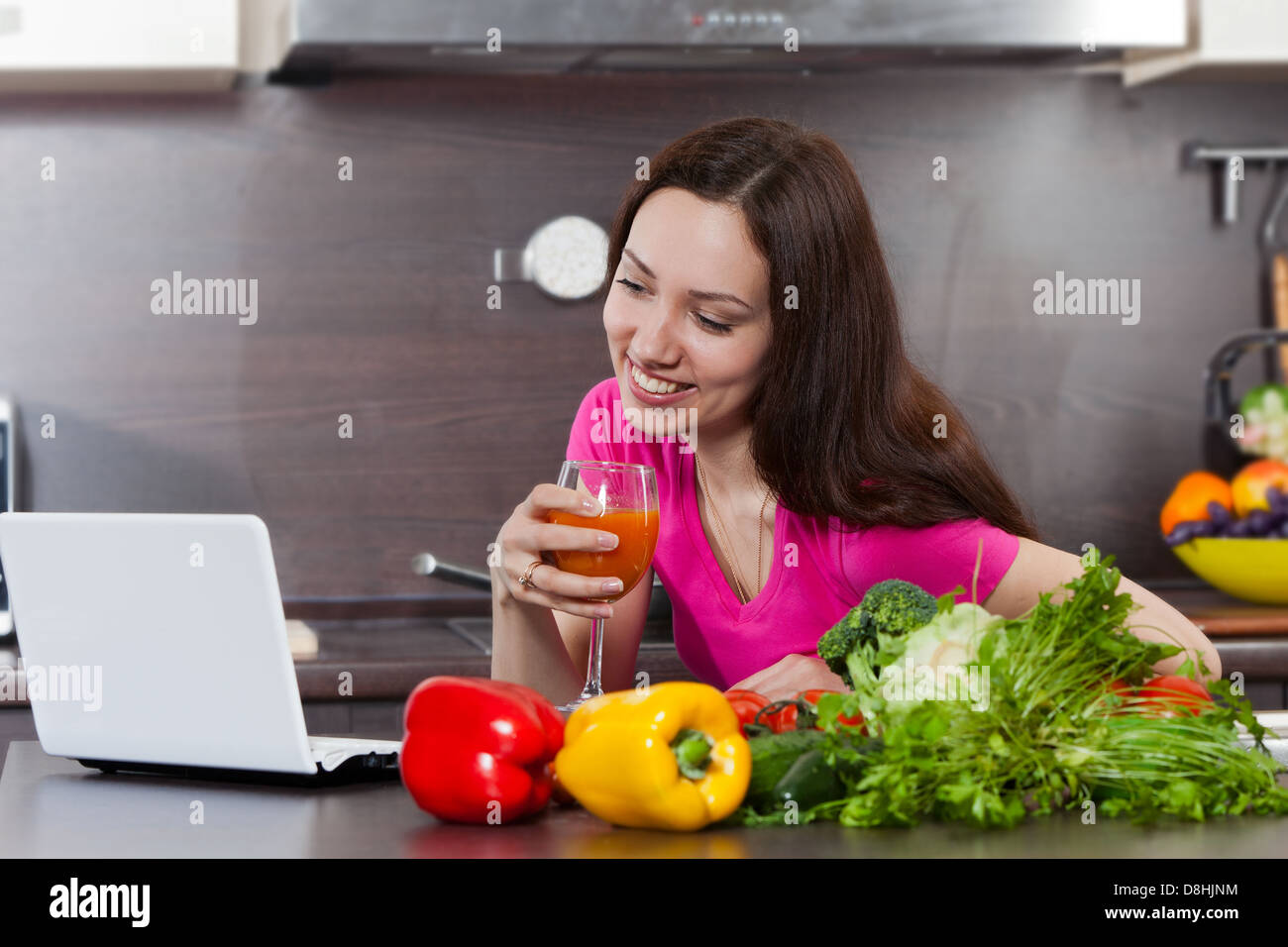 Woman drink the juice in the kitchen and looking at the computer Stock ...