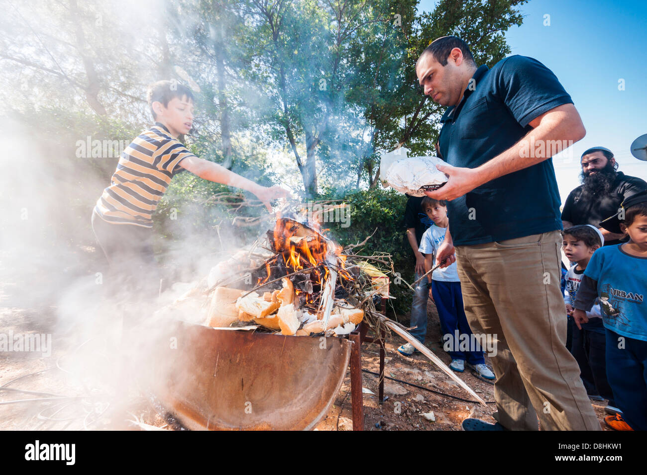 A Jewish man and boy throws a bread and wheat produts into the fire as ...