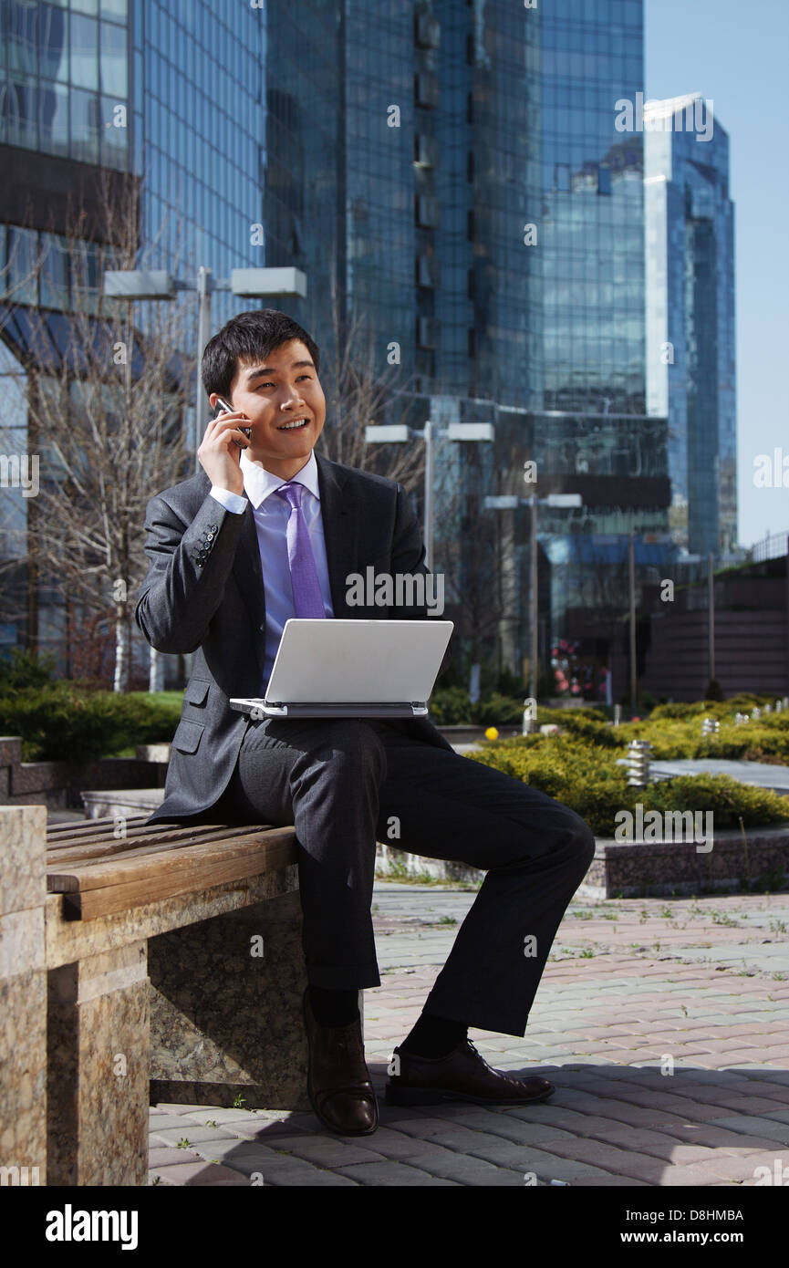 Young businessman sitting with laptop. Outdoor Stock Photo - Alamy