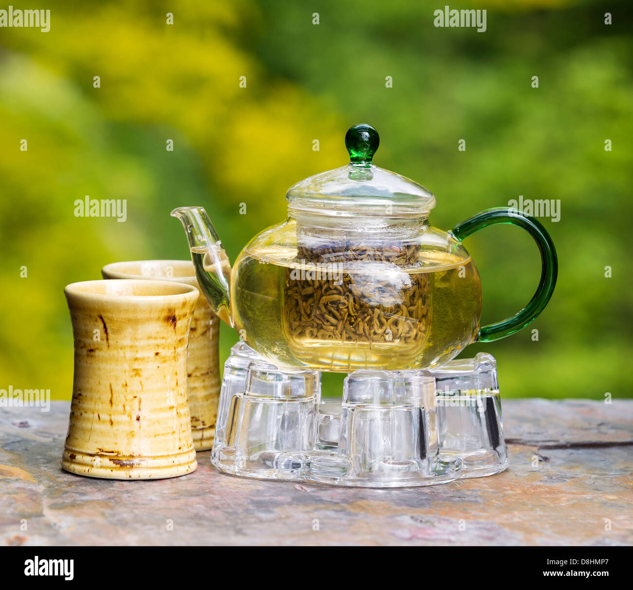 Photo of organic green tea in glass pot with ceramic cups on blurred ...