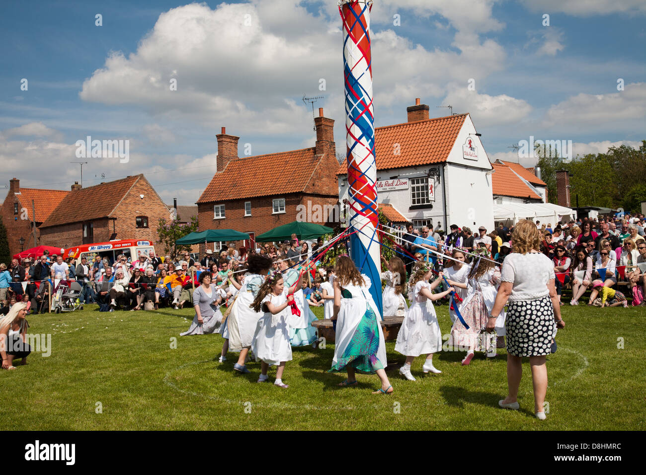 Children dance round the ancient maypole on the village green of Wellow ...