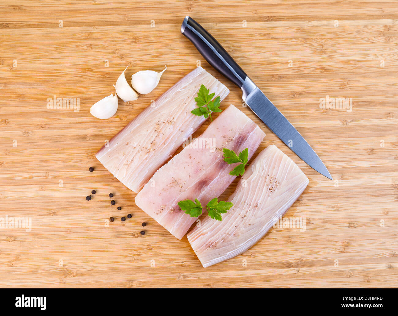 Horizontal photo of white fish fillets, knife, parsley, garlic and ...