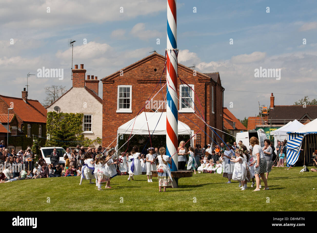 Children dance round the ancient maypole on the village green of Wellow ...