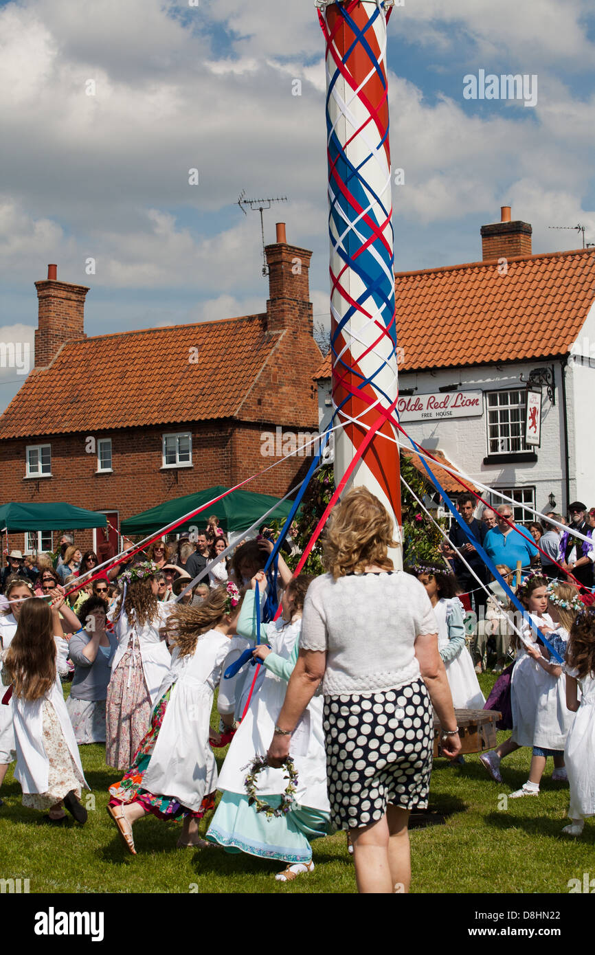 Children dance round the ancient maypole on the village green of Wellow ...