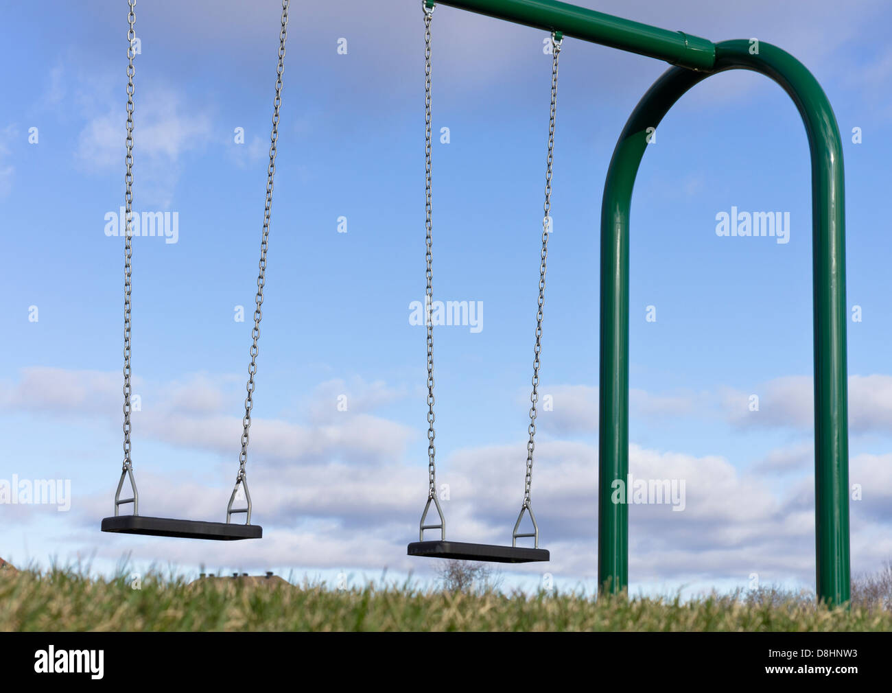 Two empty swings against blue sky with clouds Stock Photo - Alamy