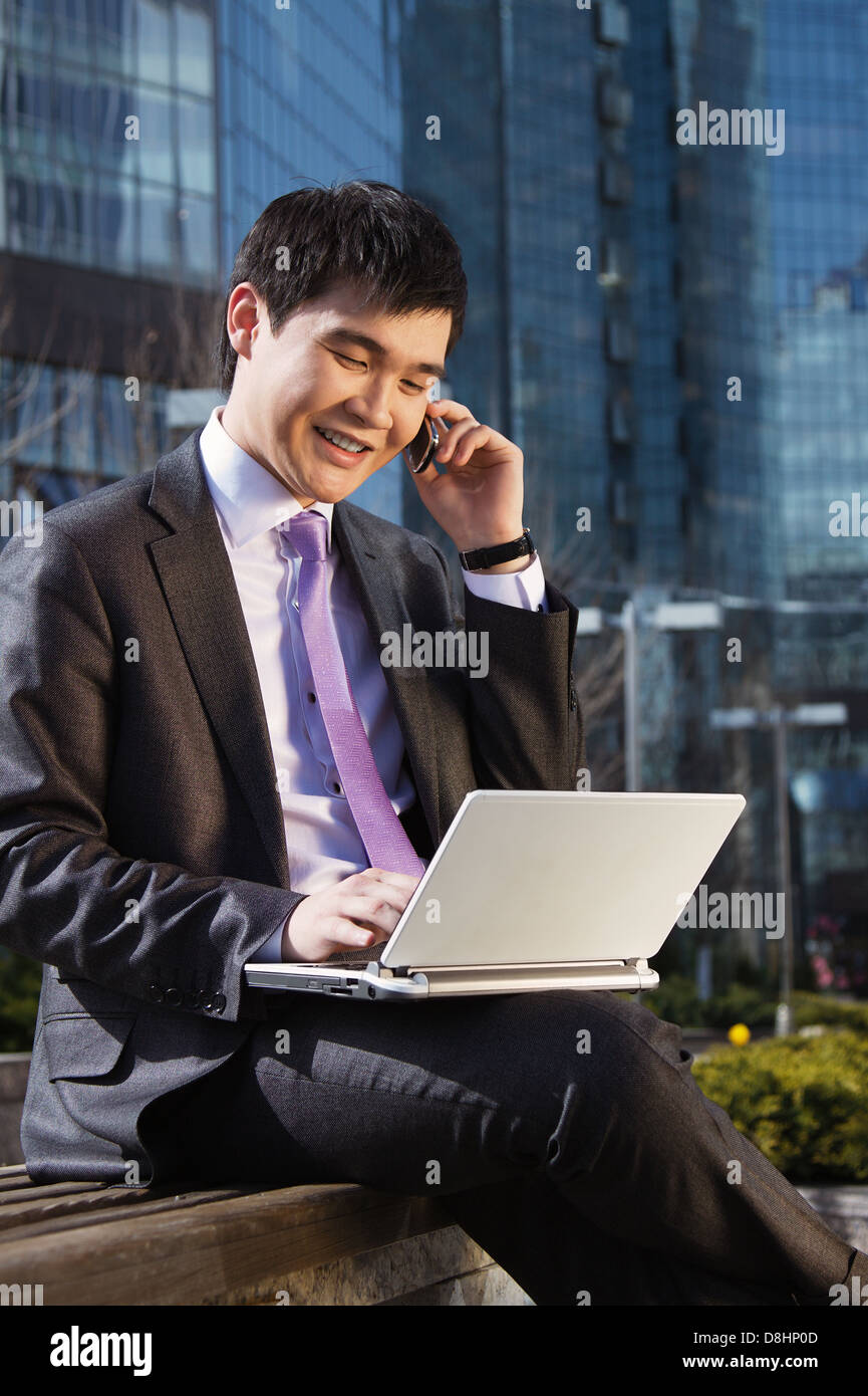 Young businessman sitting with laptop. Outdoor Stock Photo - Alamy