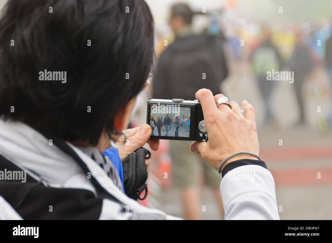 Man takes a picture with a digital point and shoot camera, people shown ...