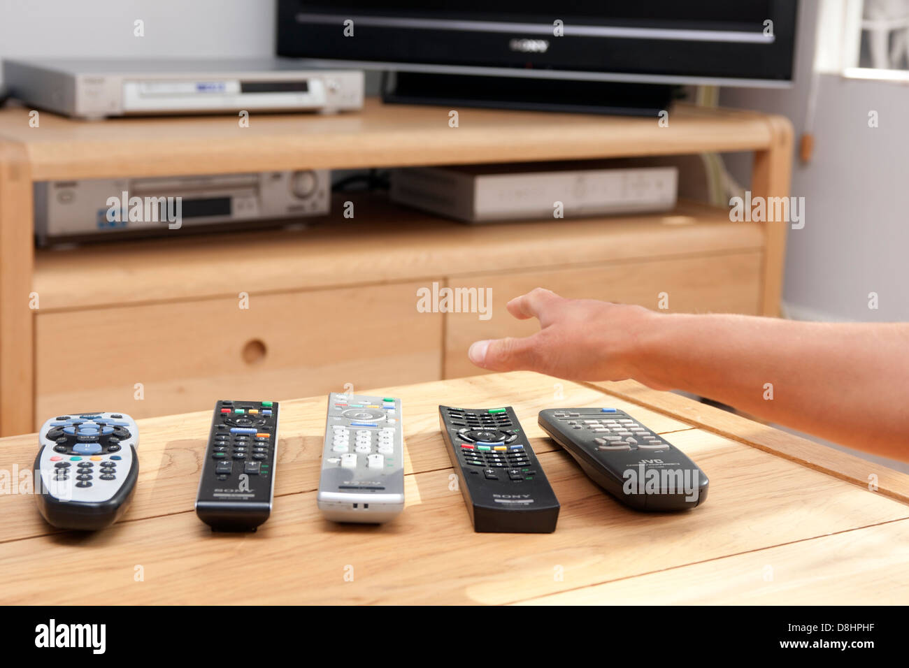 hand reaching for row of remote controls Stock Photo - Alamy