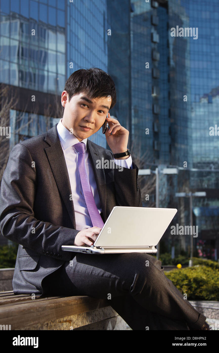 Young businessman sitting with laptop. Outdoor Stock Photo - Alamy
