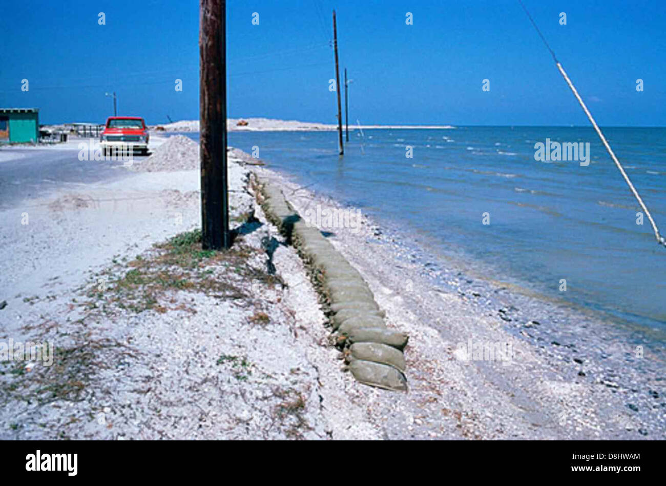 Coastal erosion is visible along a shoreline, with waves and weathering ...