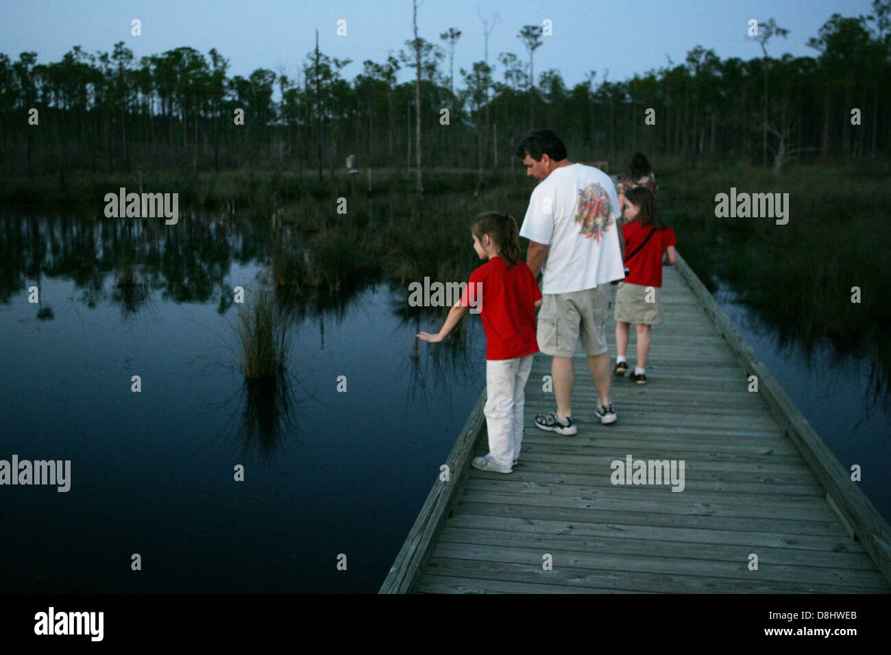 A family is enjoying scenic views of the water from a wooden catwalk ...