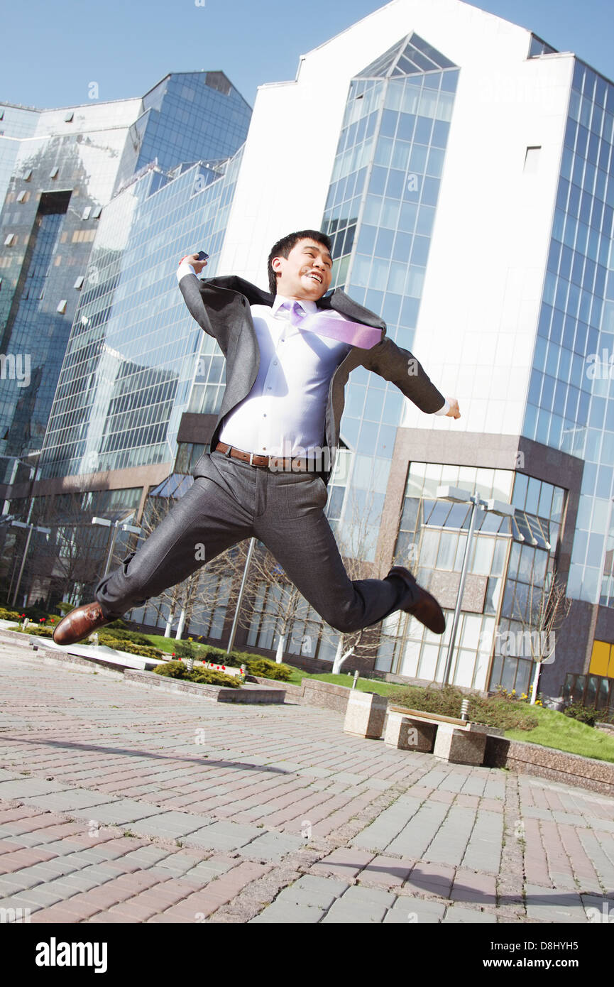 Jumping happy businessman over office buildings background Stock Photo ...