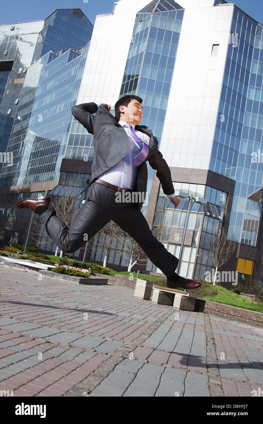 Jumping happy businessman over office buildings background Stock Photo ...
