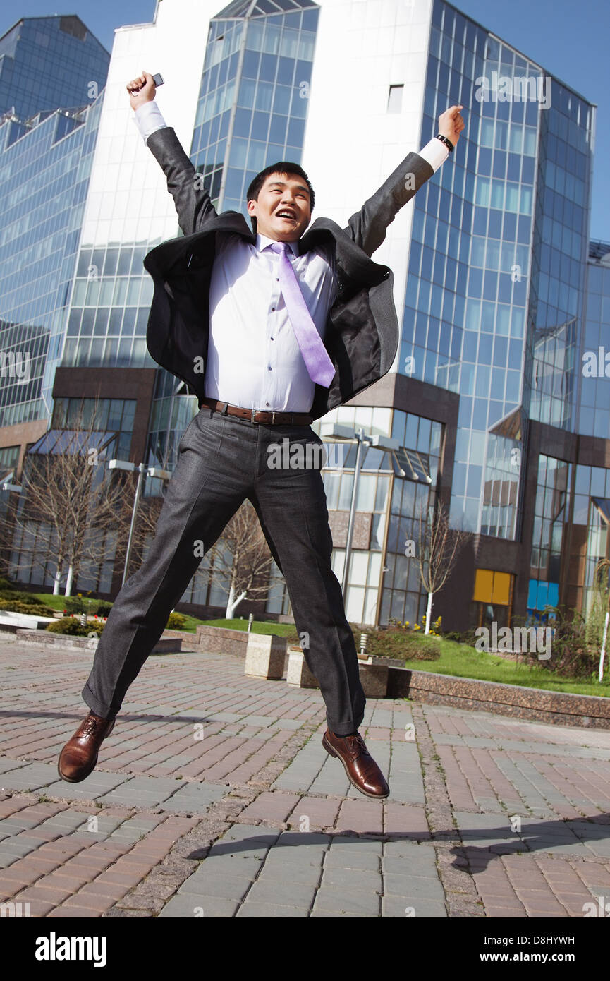 Jumping happy businessman over office buildings background Stock Photo ...