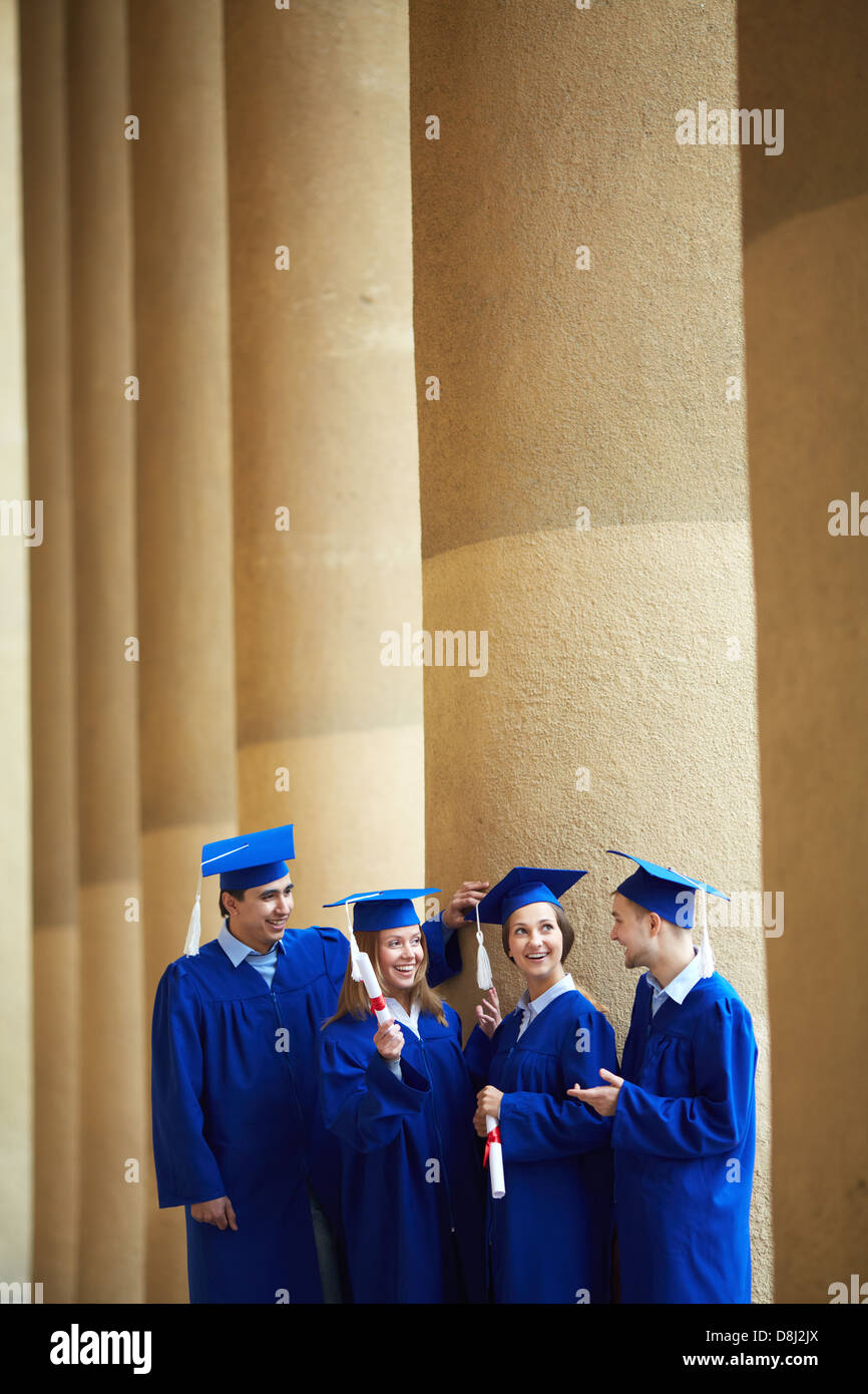 Group of smart students in graduation gowns having chat Stock Photo - Alamy