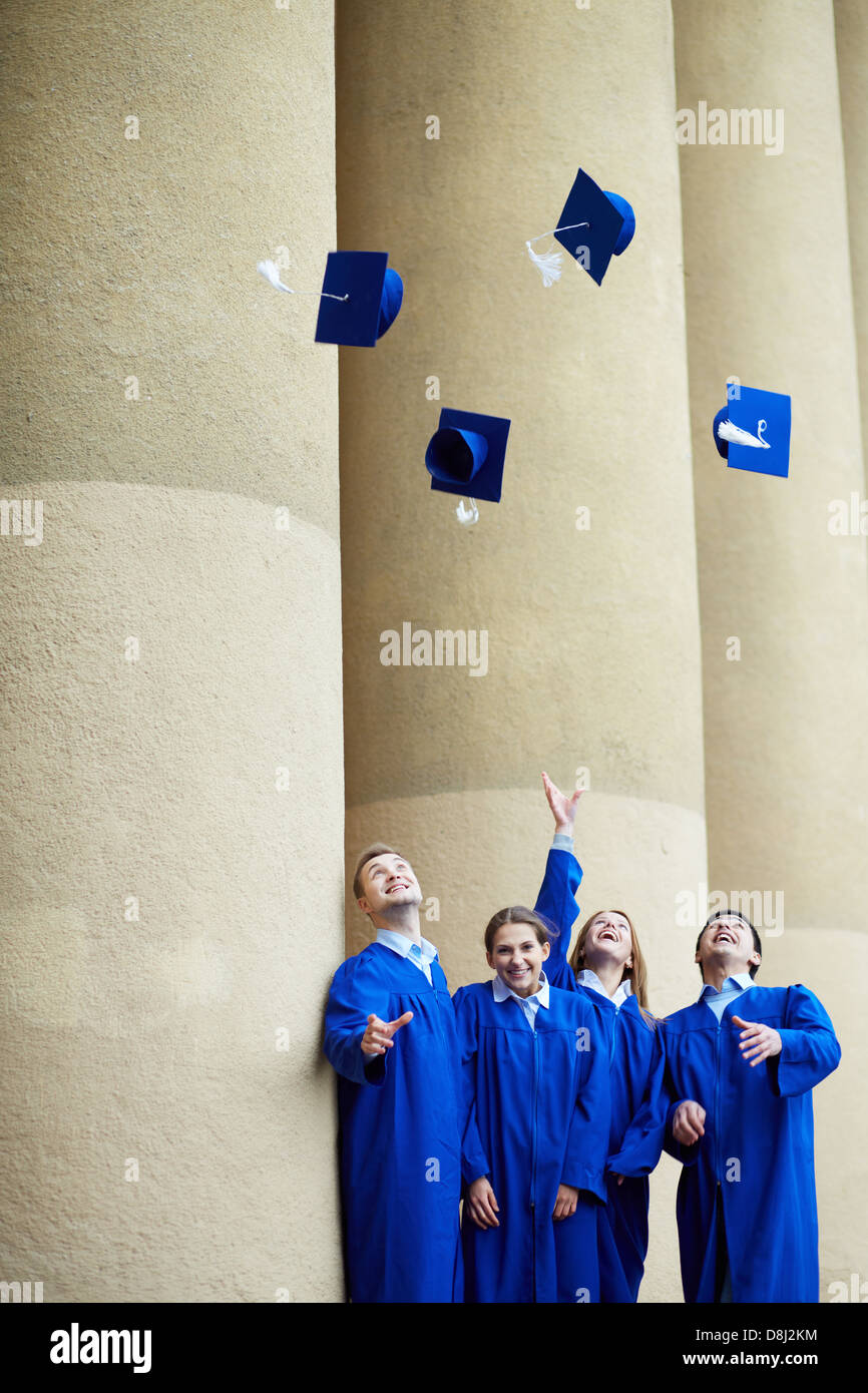 Group of smart students in graduation gowns throwing their hats Stock ...