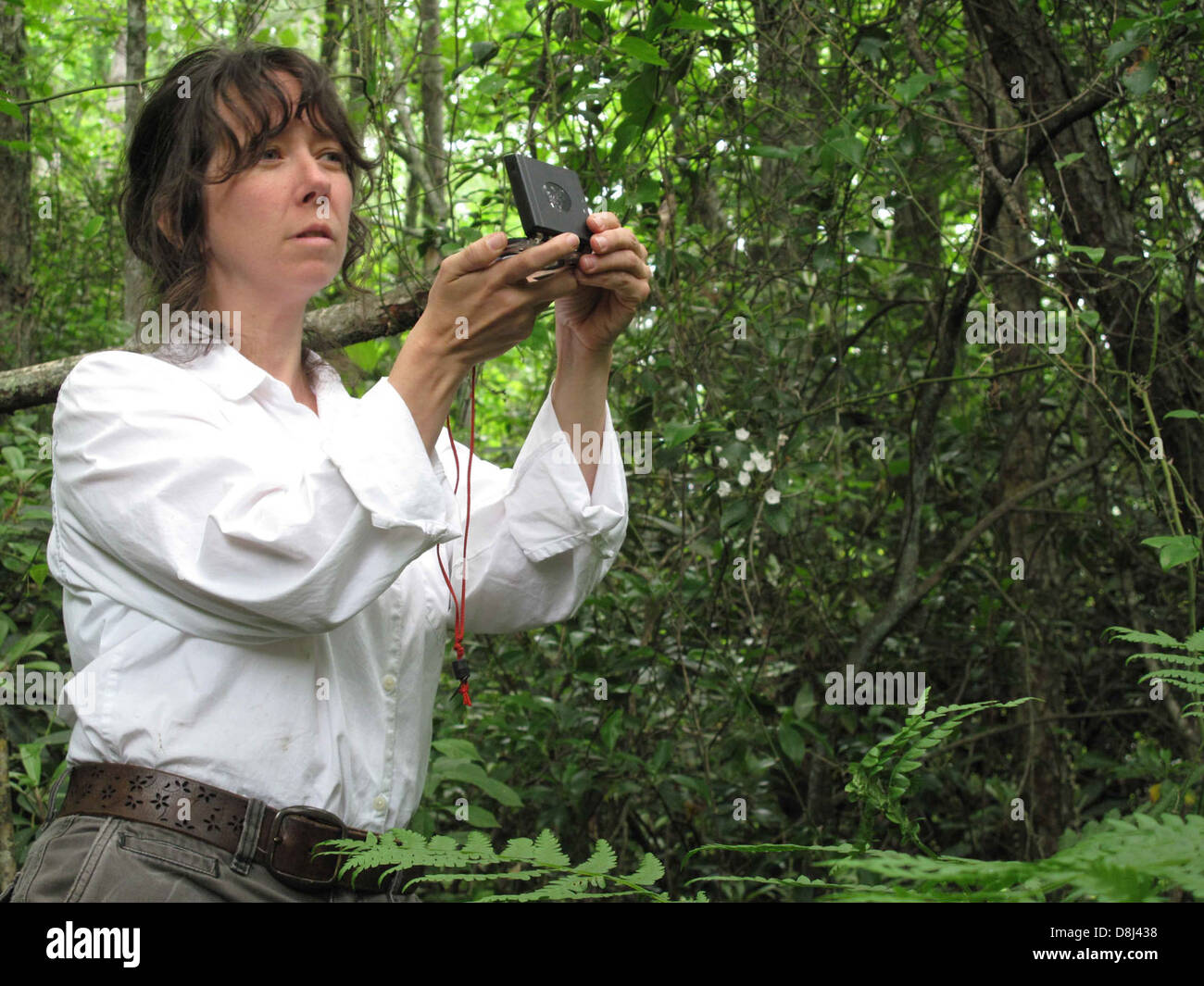 A woman is using a compass to take a bearing during an outdoor ...